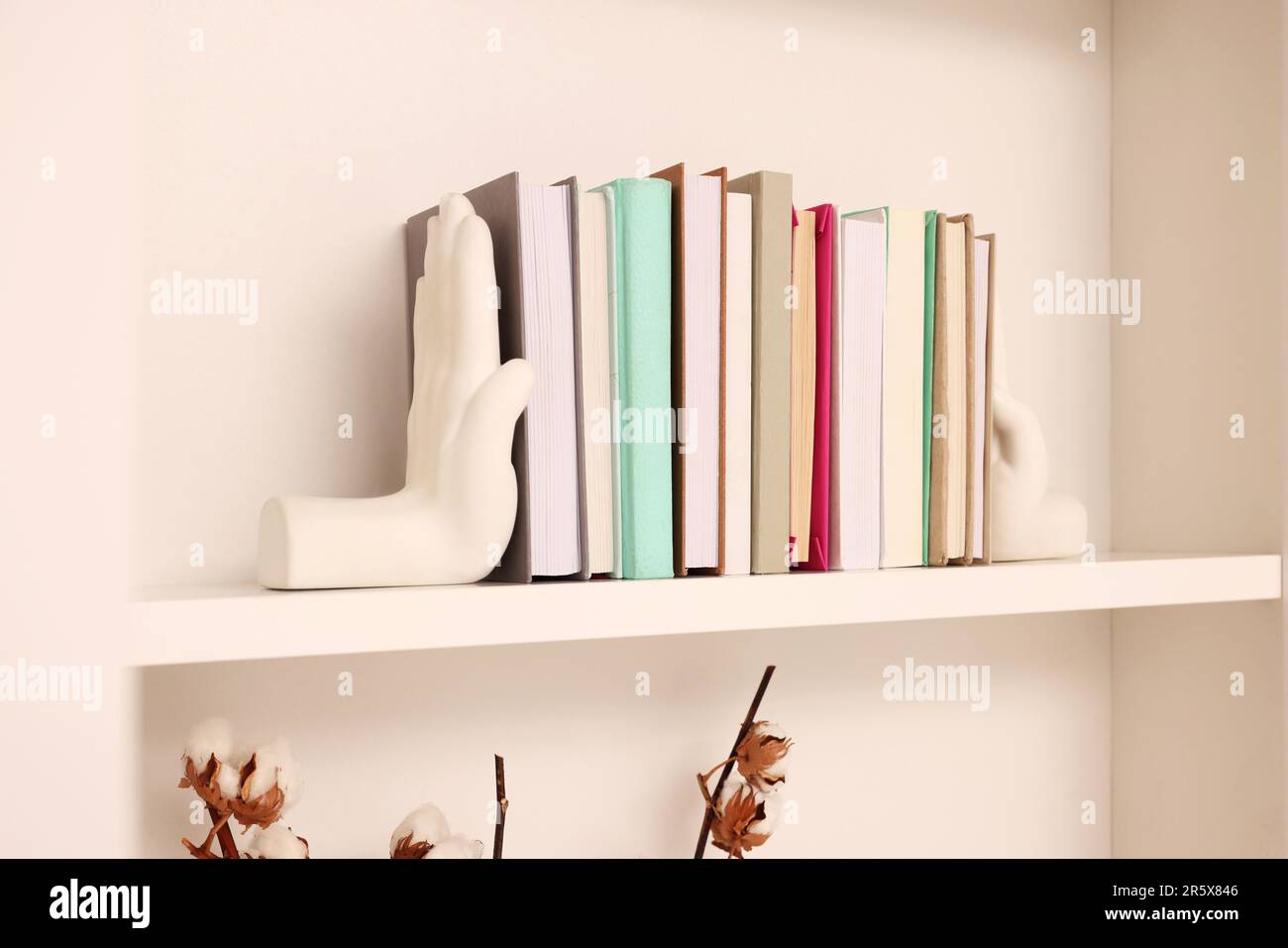 Beautiful hand shaped bookends with books on shelf indoors Stock Photo ...