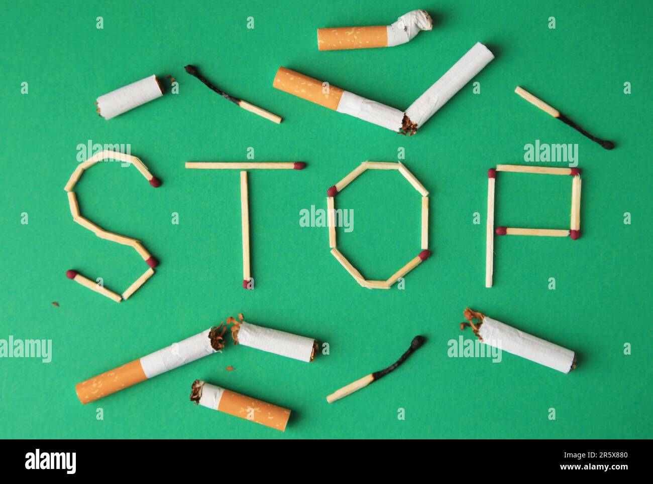 Word Stop made of matches and cigarette stubs on green background, flat ...