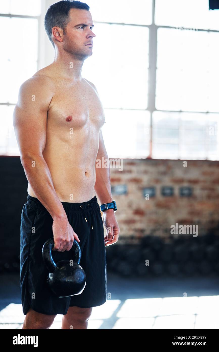 Never drift away from lifting. a young man lifting kettlebells in a gym ...