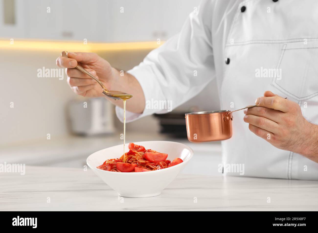 Professional chef pouring sauce into delicious spaghetti at marble ...