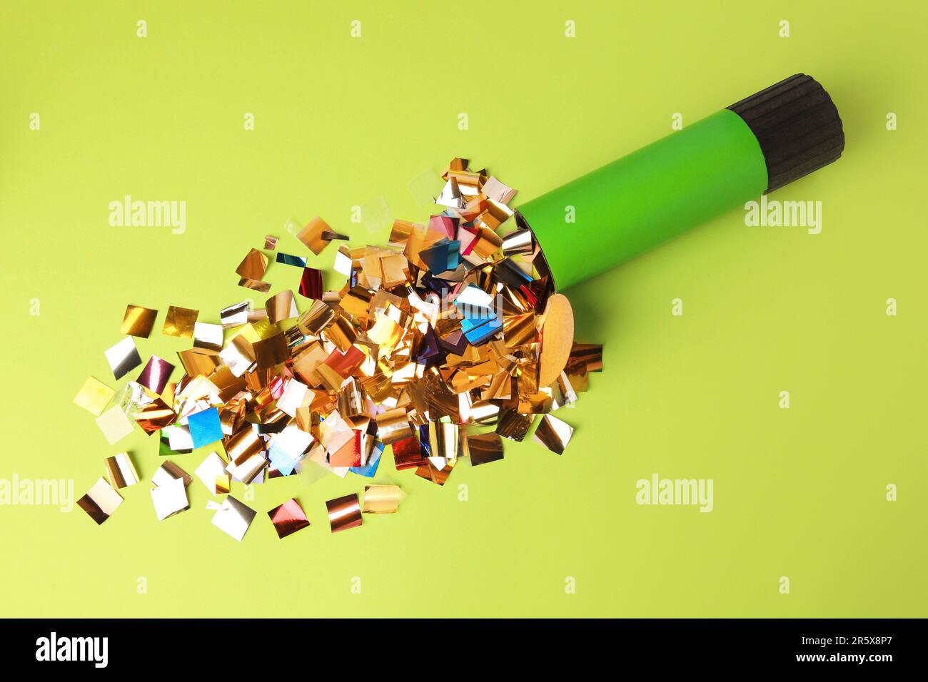 Shiny colorful confetti bursting out of party popper on green ...