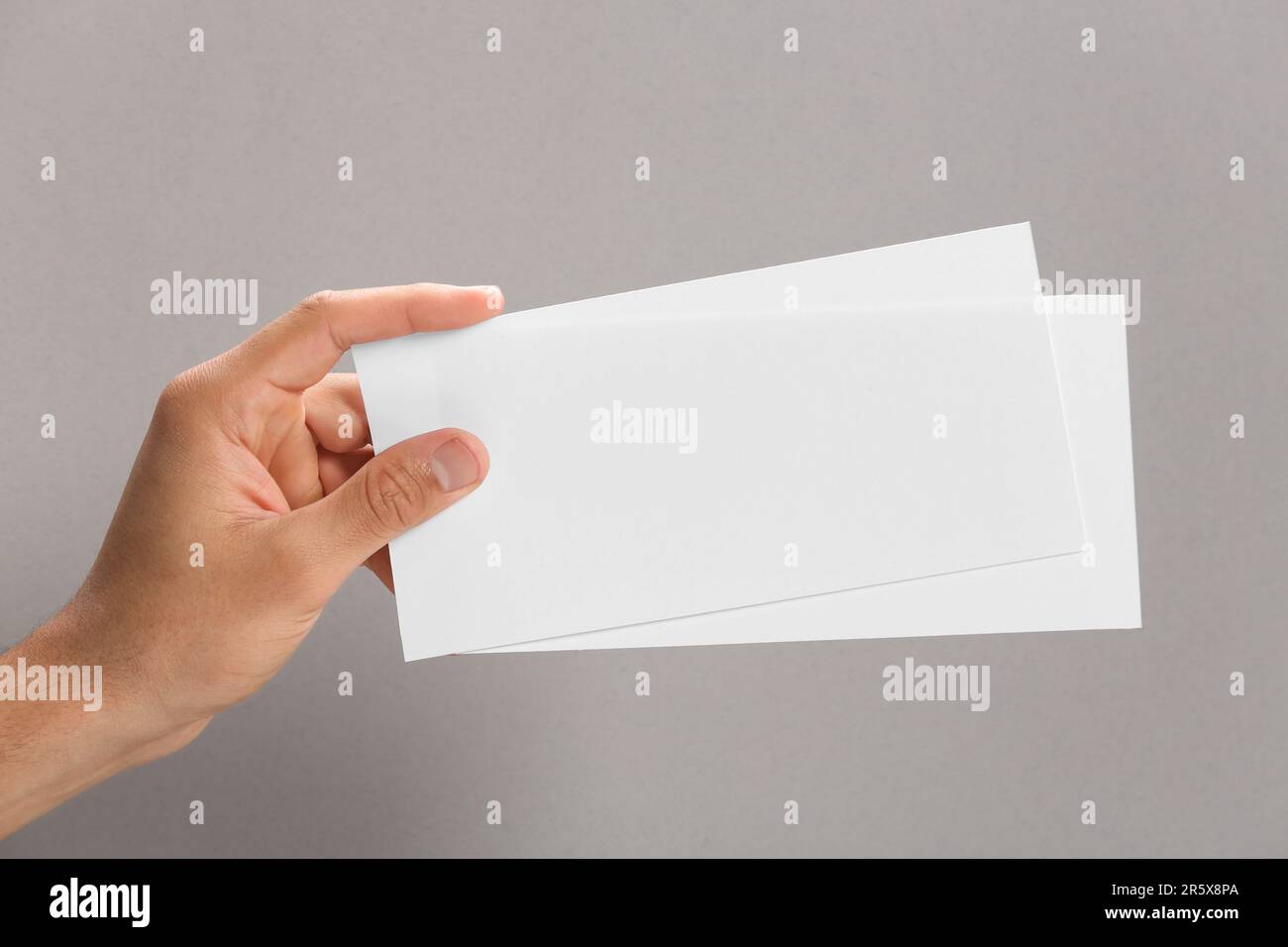 Man holding flyers on grey background, closeup. Mockup for design Stock ...