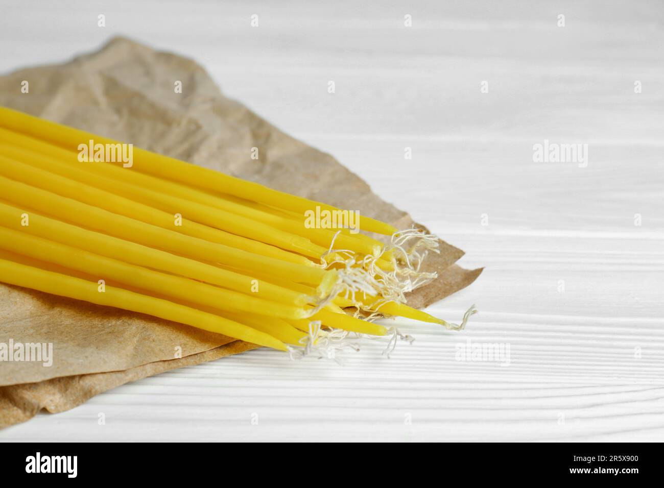 Parchment and church candles on white wooden table, closeup. Space for ...