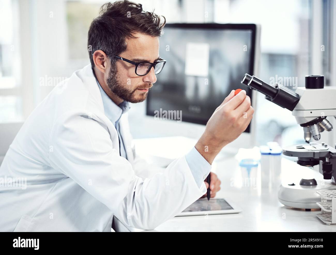 Small yet important. a focused young male scientist examining a test ...