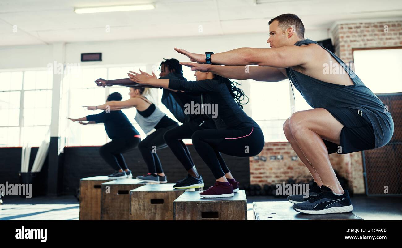 Reach out. a focused group of young people doing lunges on crates as ...