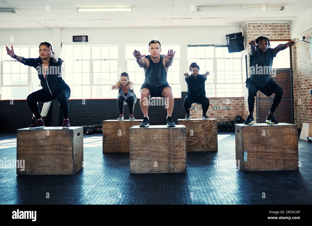 Keep your back straight. a focused group of young people doing lunges ...