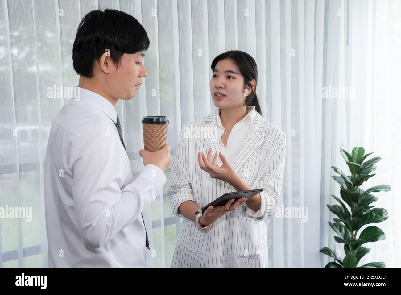 Manager advising guiding younger colleague with tablet in workplace ...