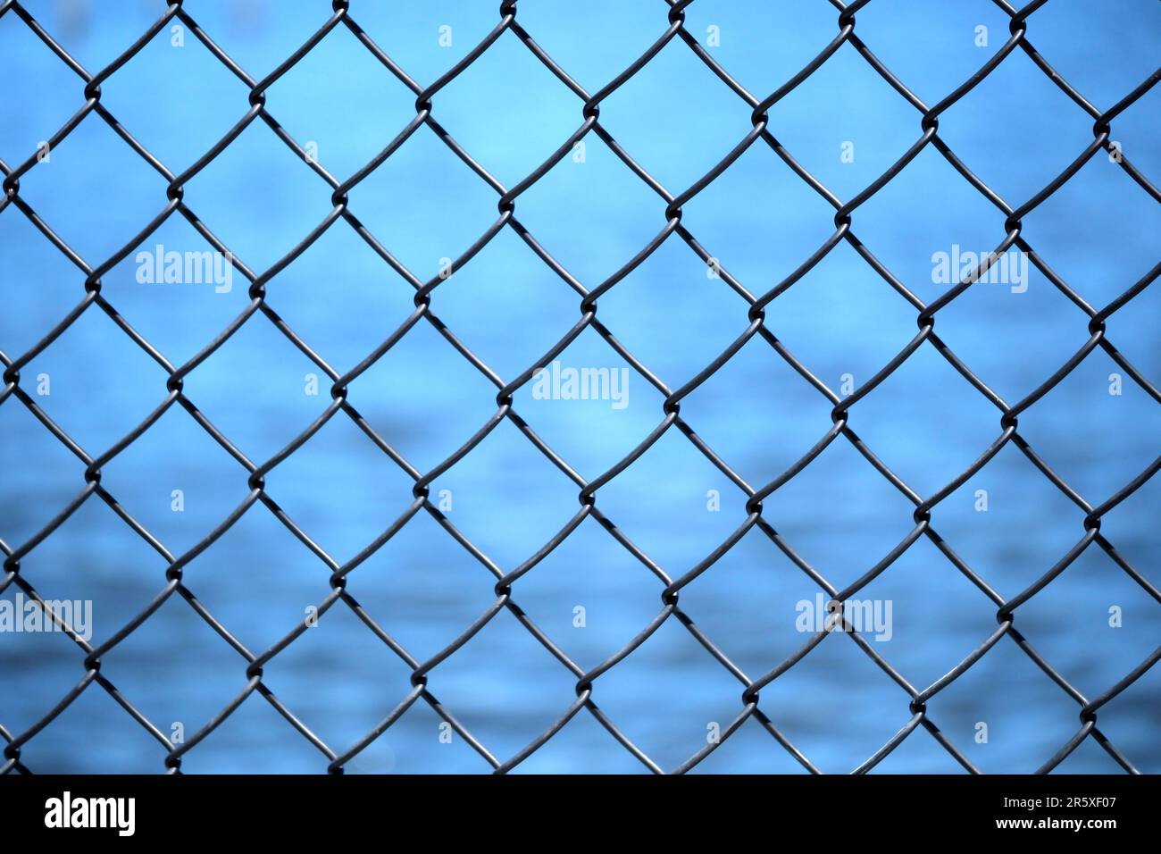 A close up of a metal chain link fence against defocused waterfront ...