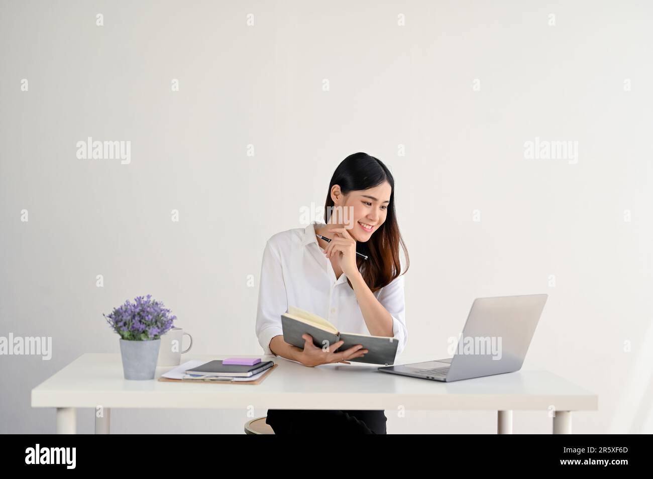 A charming and focused young Asian businesswoman is looking at her ...