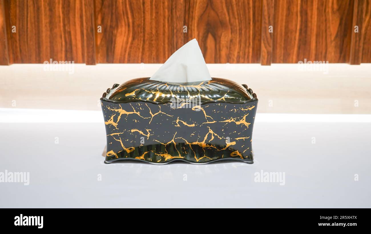 This tissue box holder features a sleek black design with golden ...