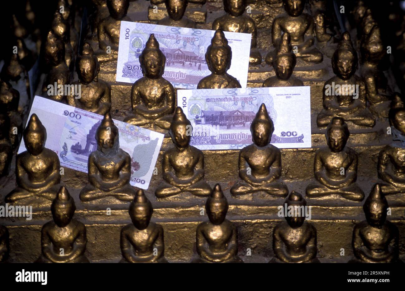 Money offerings to tiny statues of the Buddha in a Khmer temple in ...