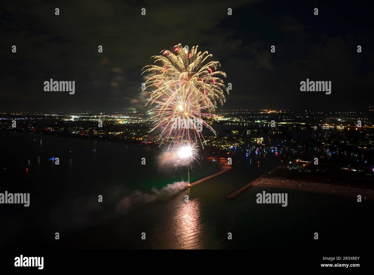 Aerial view of bright fireworks exploding with colorful lights over sea ...