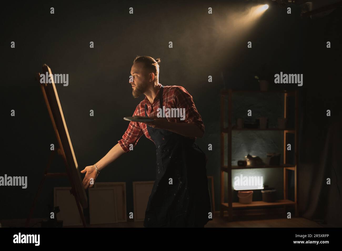 Talented artist working in dark creative studio creating modern ...