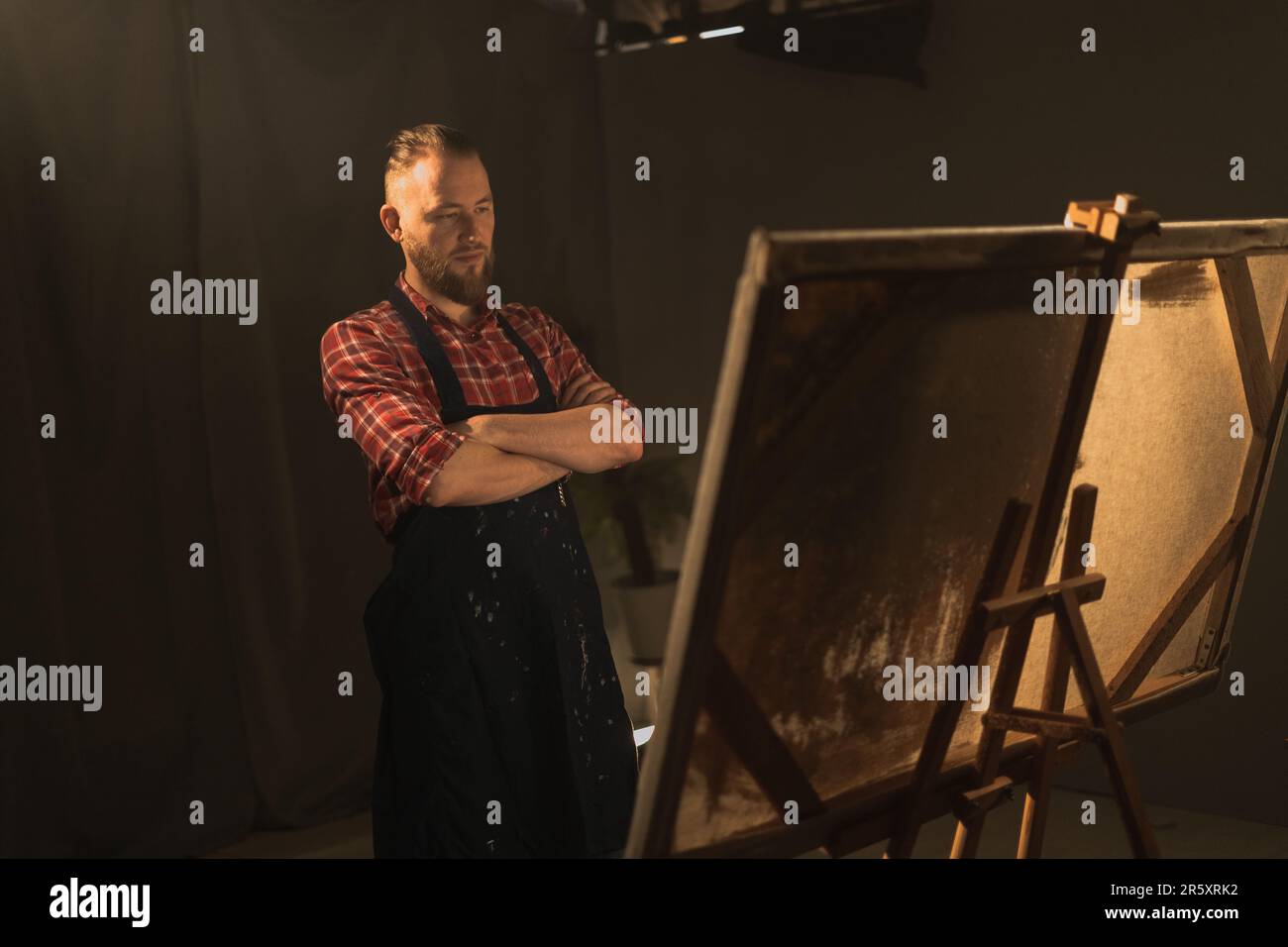 Talented Male Artist working in dark creative studio looking at modern ...