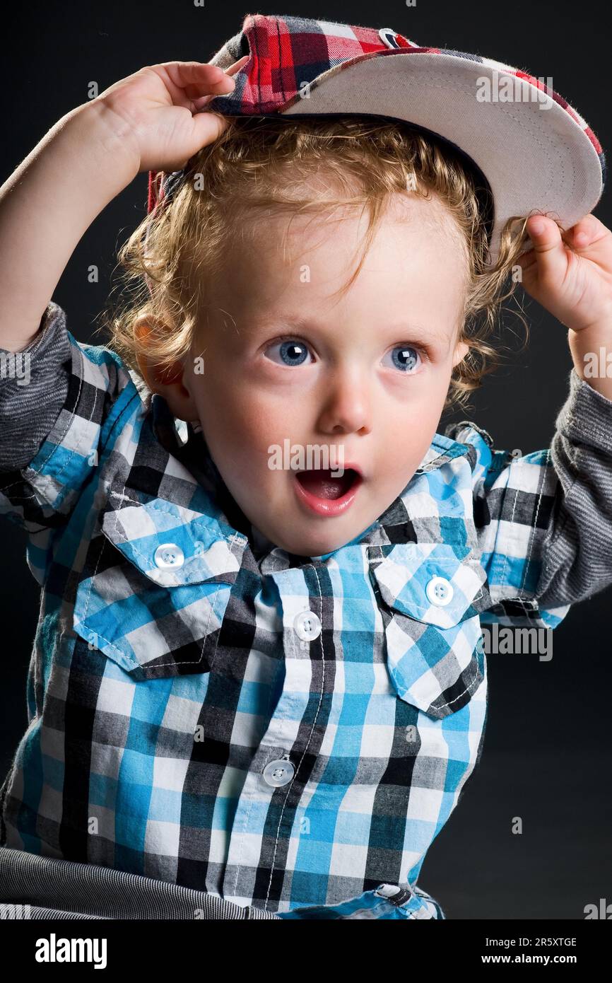 Casual cool young child with cap in front of grey background Stock ...