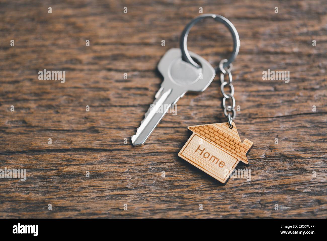 House key on a house shaped keychain resting on wooden floorboards ...