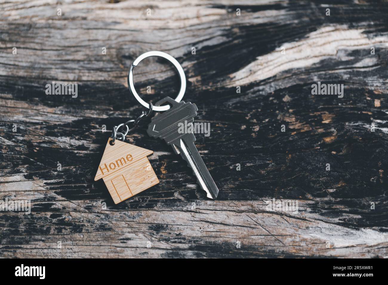 House key on a house shaped keychain resting on wooden floorboards ...