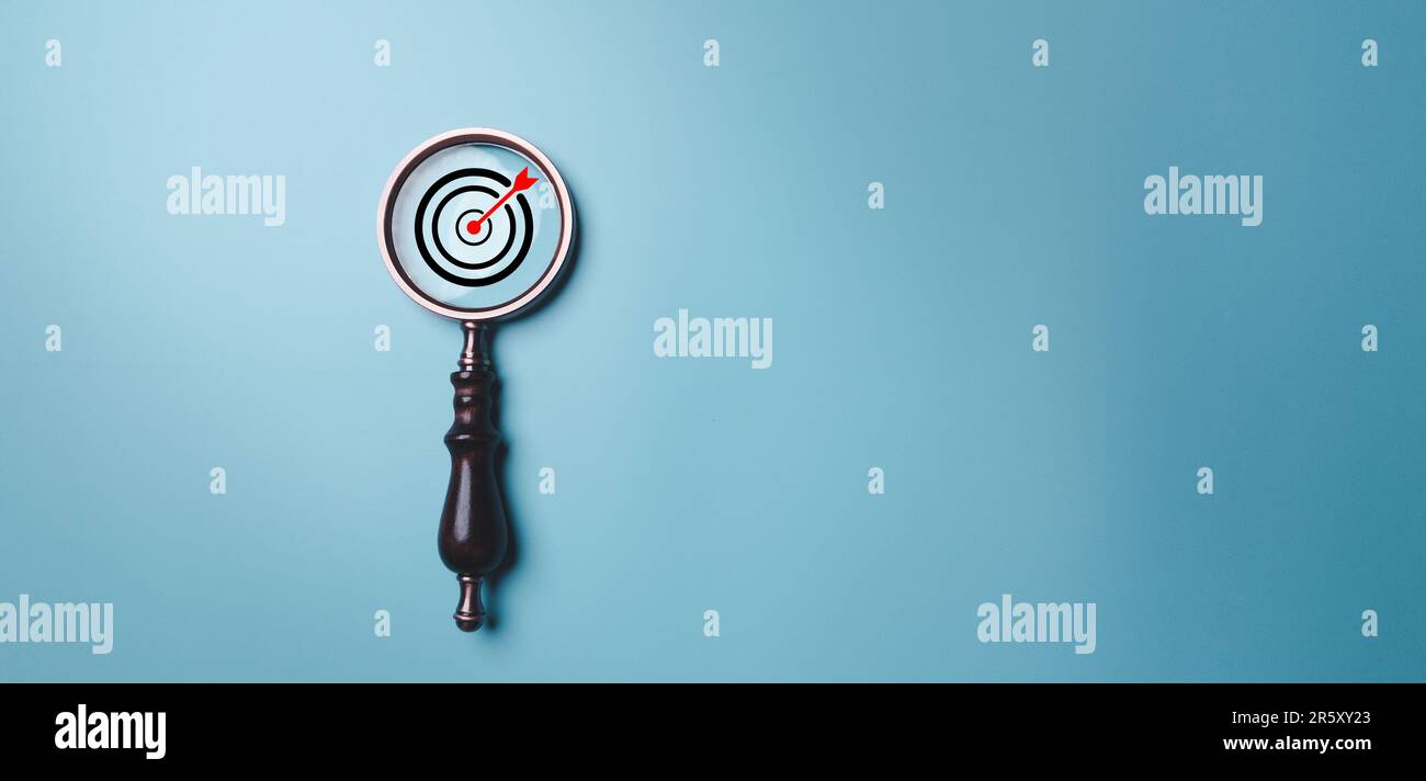 Target board inside vintage magnifying glass for focus business objective on blue background and ...