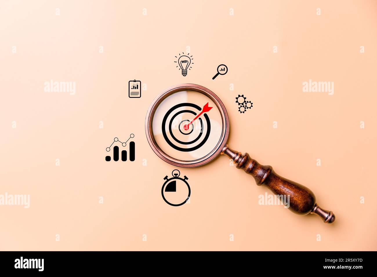 Hand holding target board inside vintage magnifying glass for focus business objective on orange ...