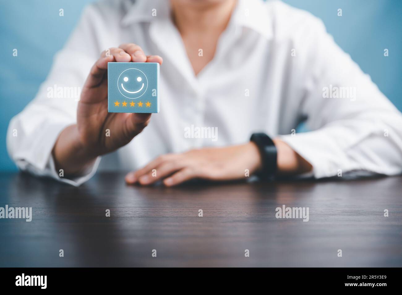 Woman hand holding happy face smile face icon on cube blue object ...