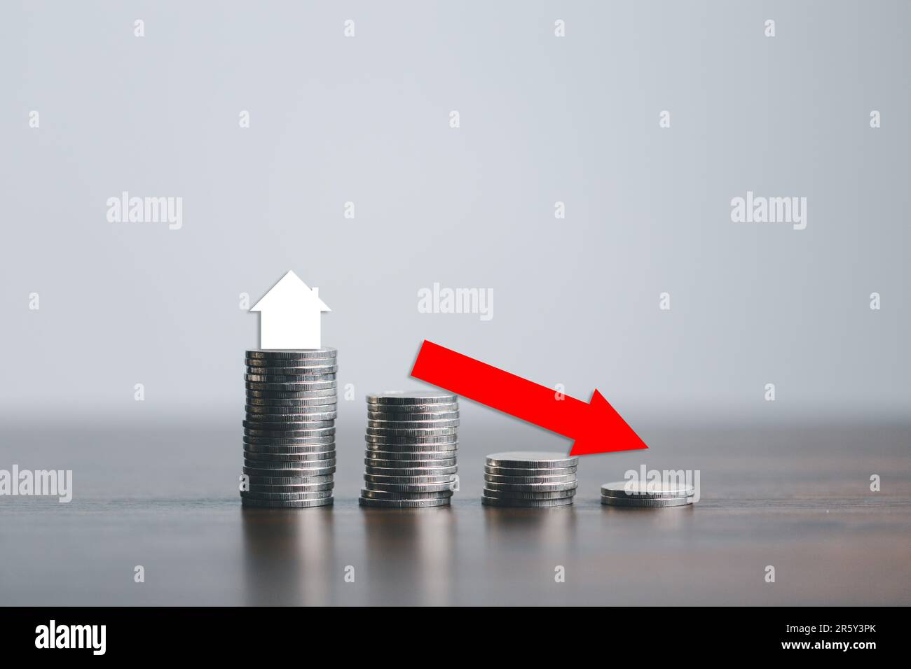 Real estate market, graph, arrow down. Mini house and a stack of coins ...