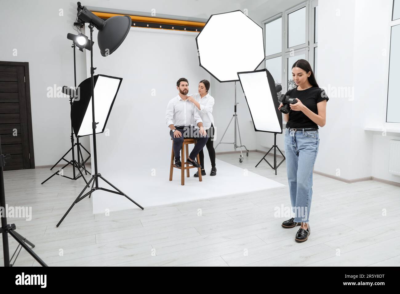 Professional photographer and stylist working with model in modern ...