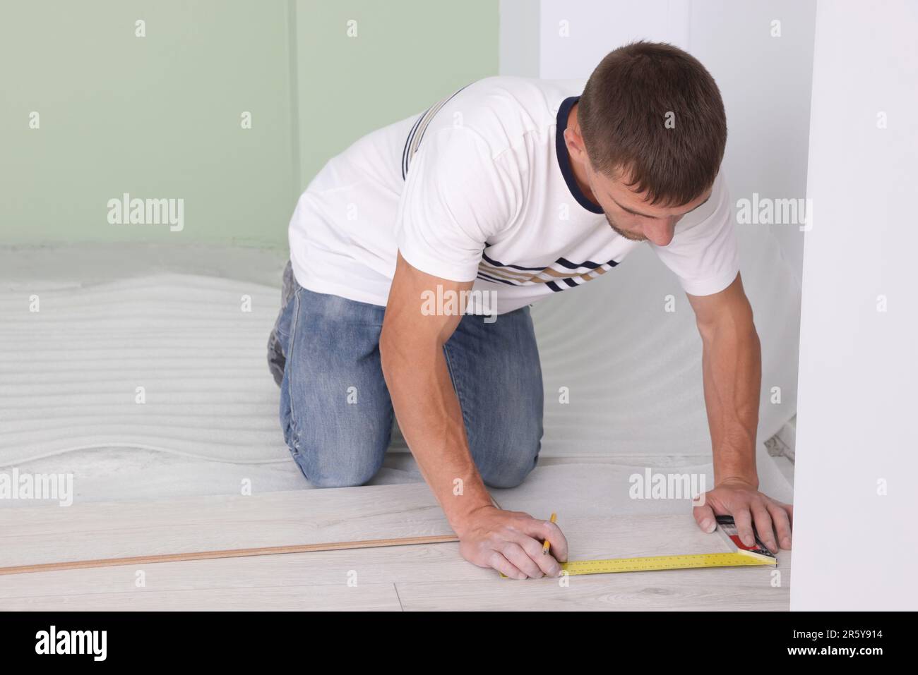 Man using measuring tape during installation of laminate flooring in ...