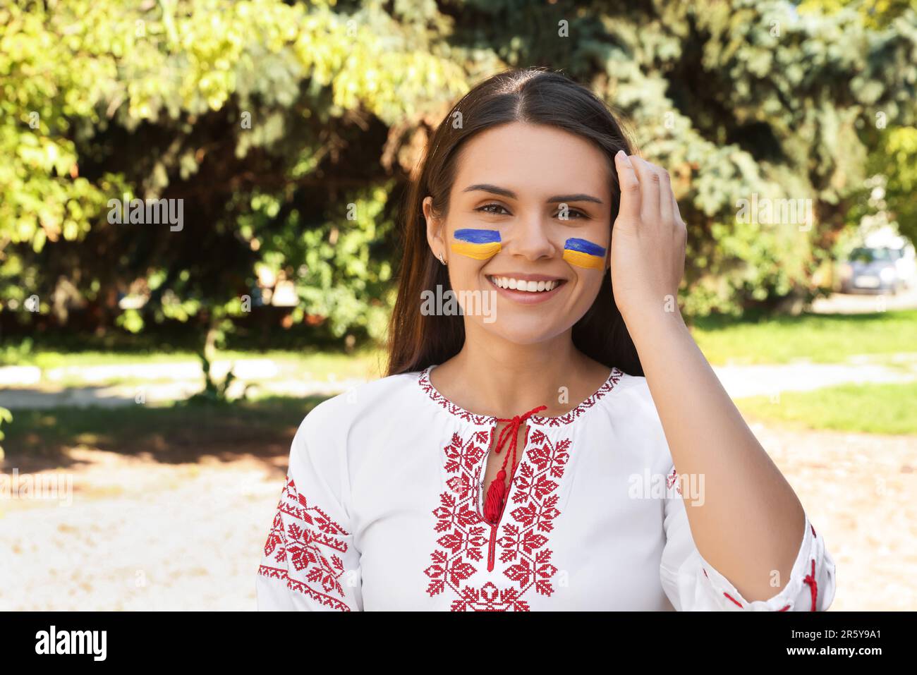 Young woman with drawings of Ukrainian flag on face in park Stock Photo ...