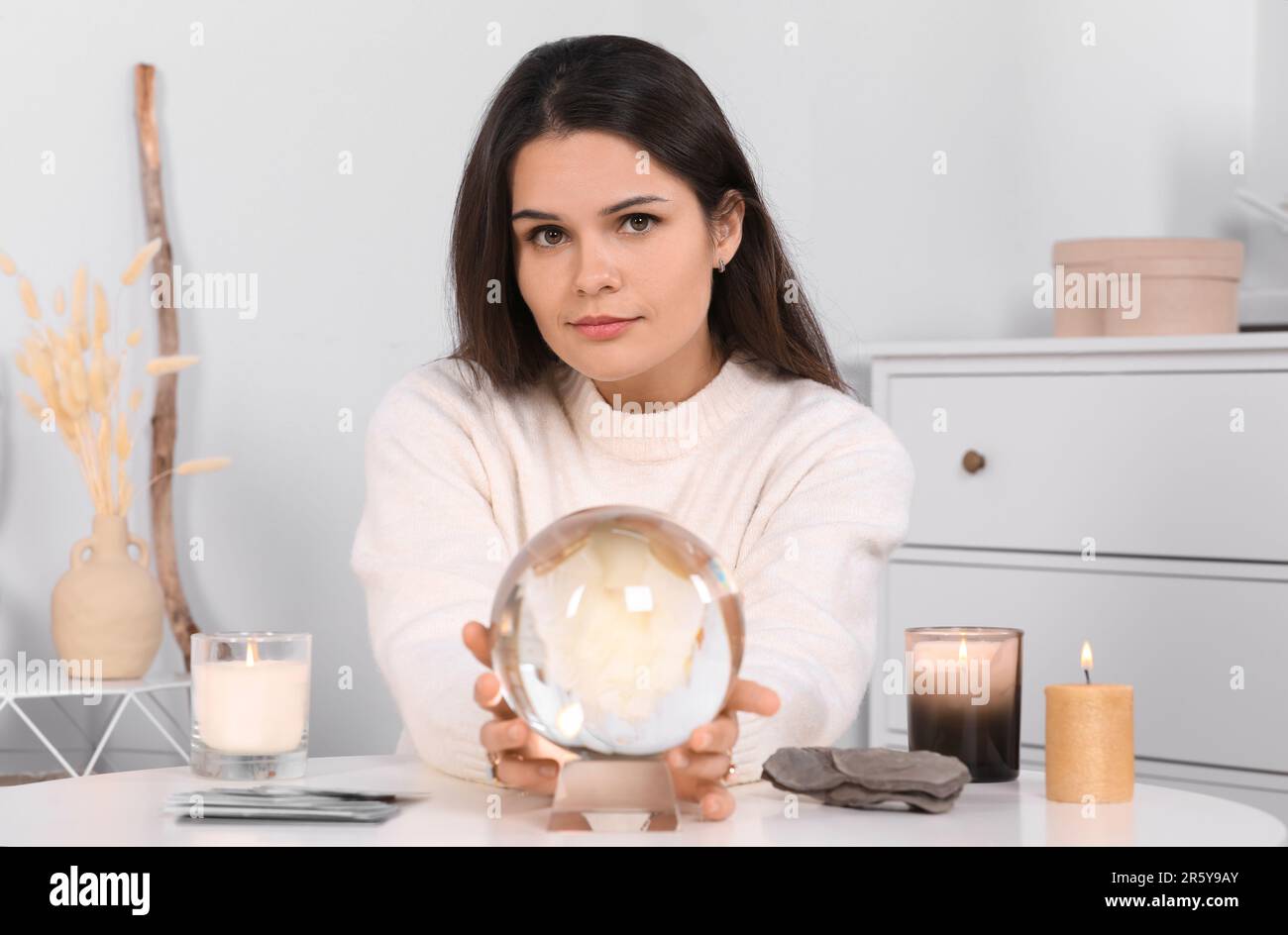 Soothsayer Using Crystal Ball To Predict Future At Table In Room Stock