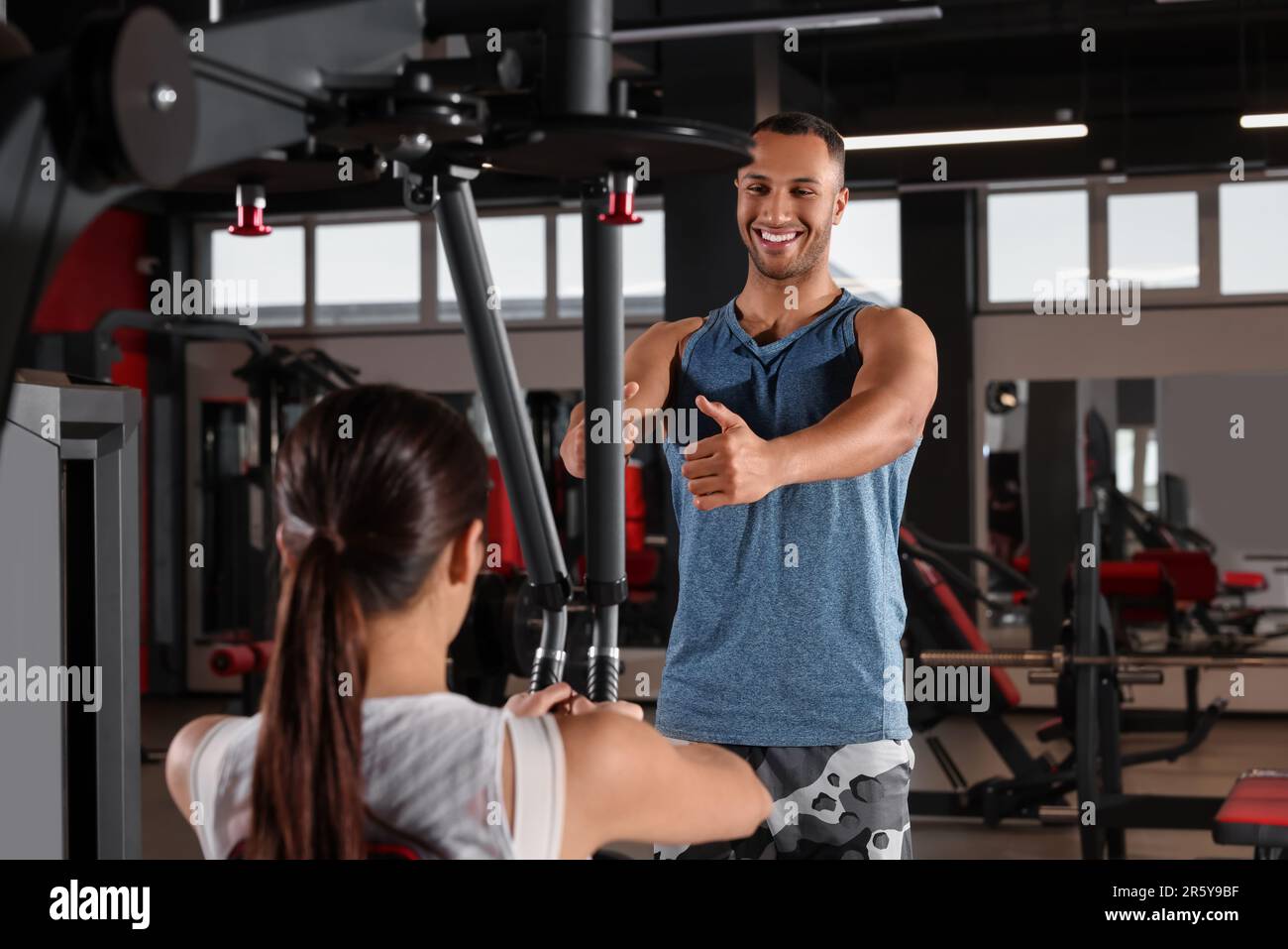 Happy trainer explaining woman how to do exercise properly in modern ...