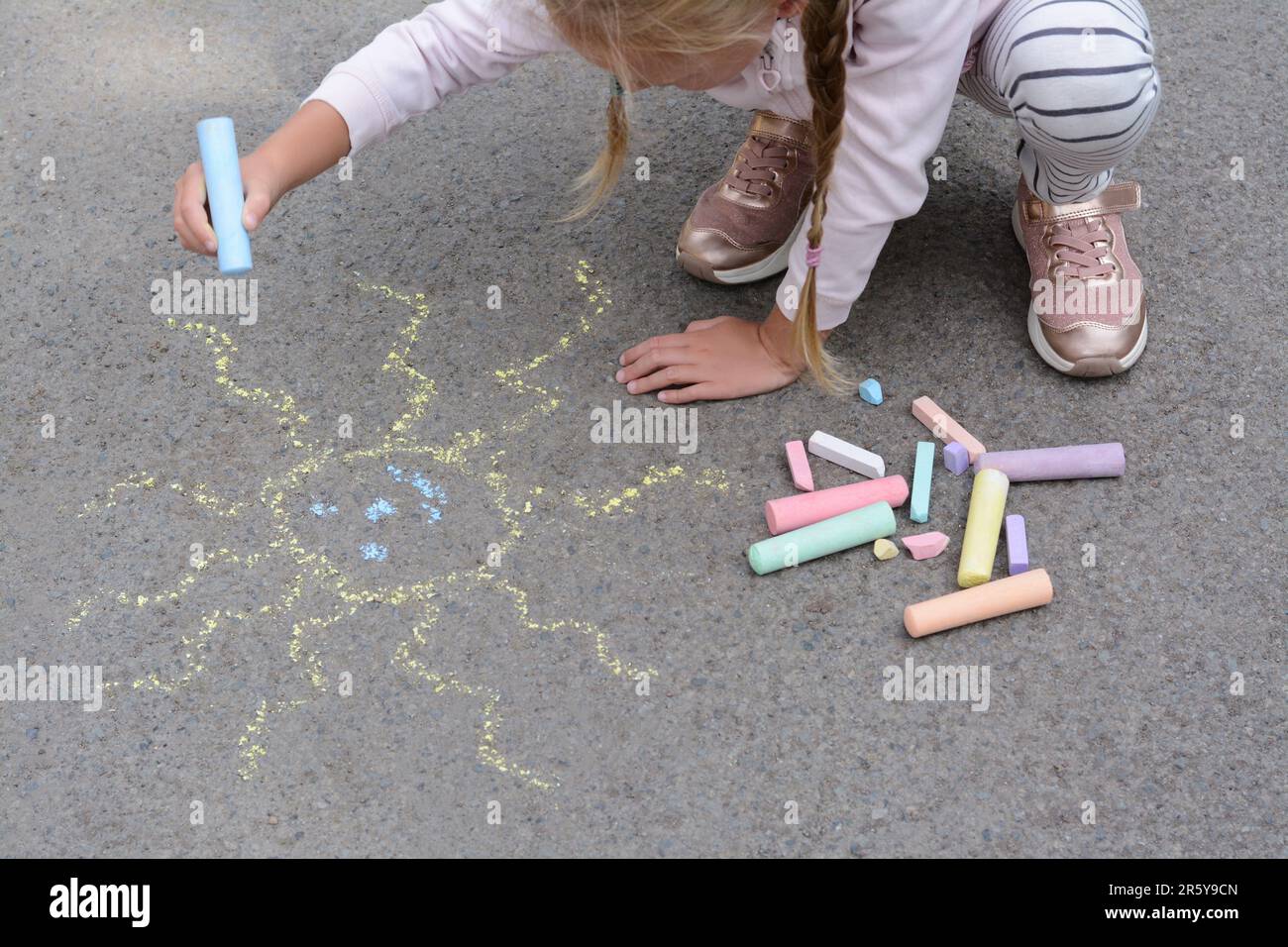 Little child drawing sun with chalk on asphalt, closeup Stock Photo - Alamy