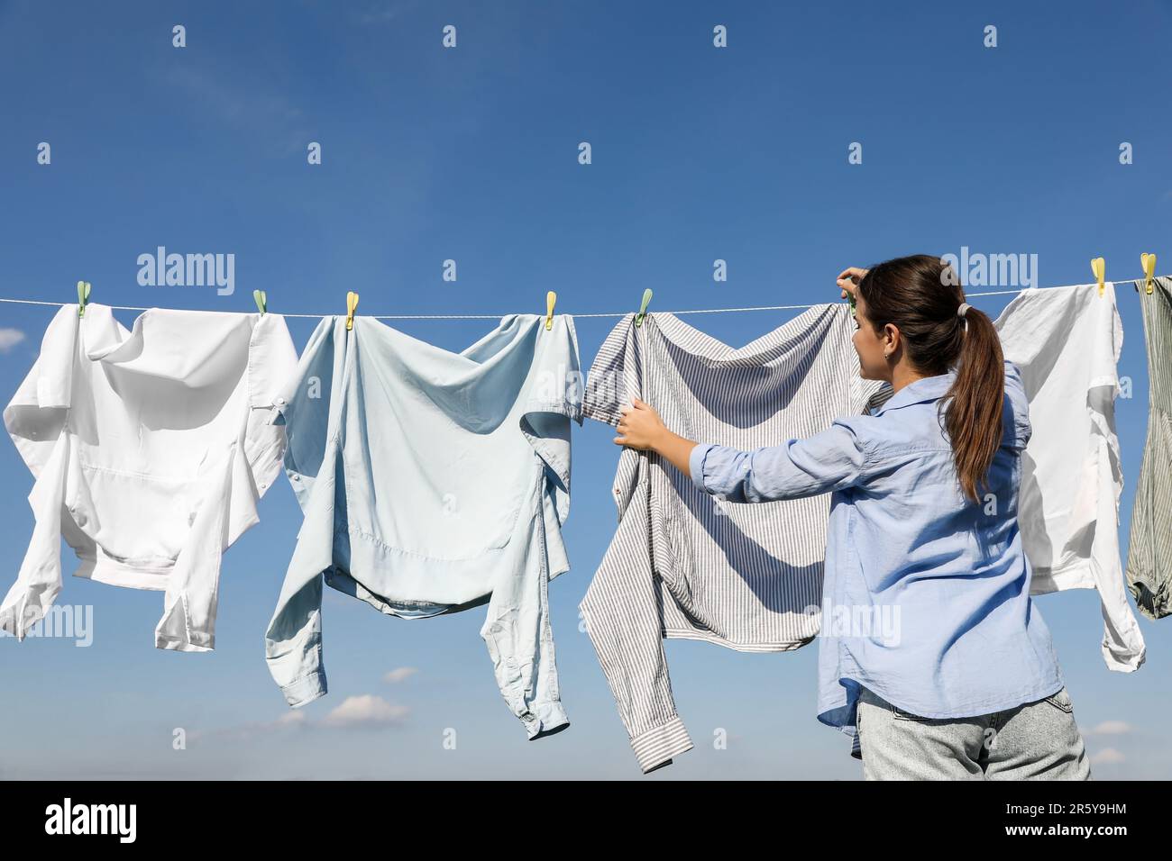 Woman hanging clothes with clothespins on washing line for drying ...