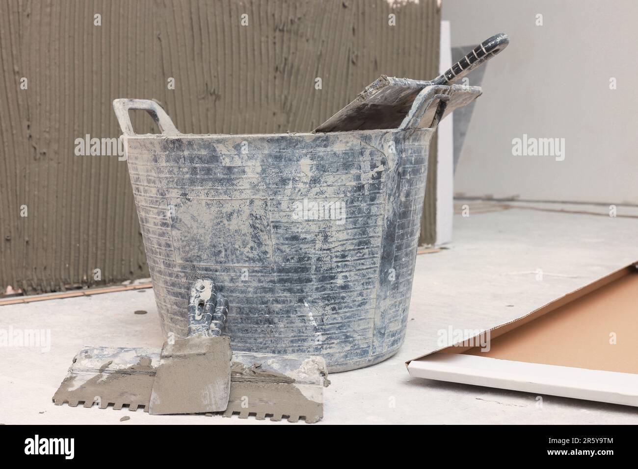 Bucket near white wall with adhesive mix for tile installation indoors ...