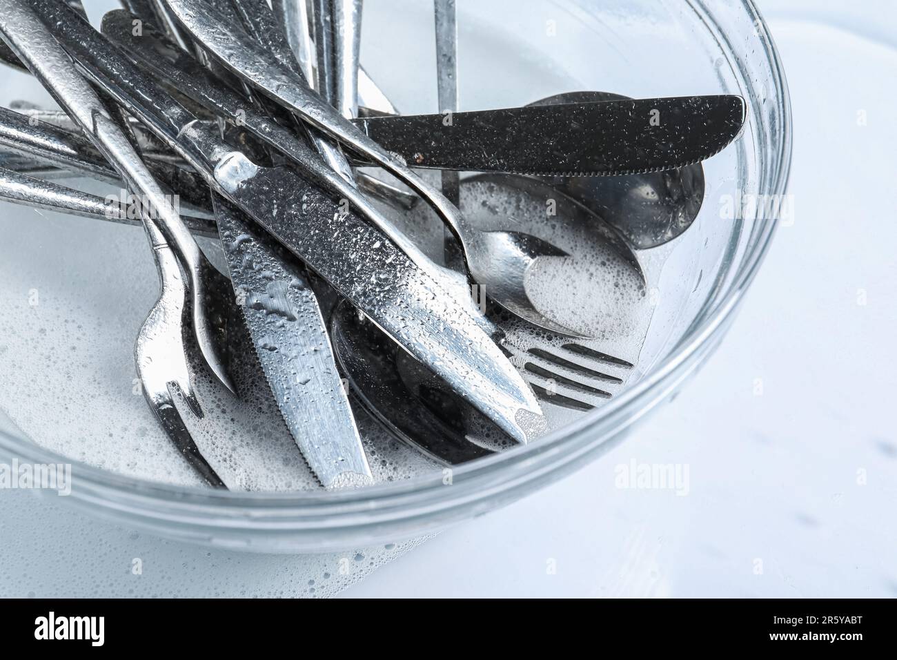 Glass bowl with silverware in foam, above view Stock Photo - Alamy