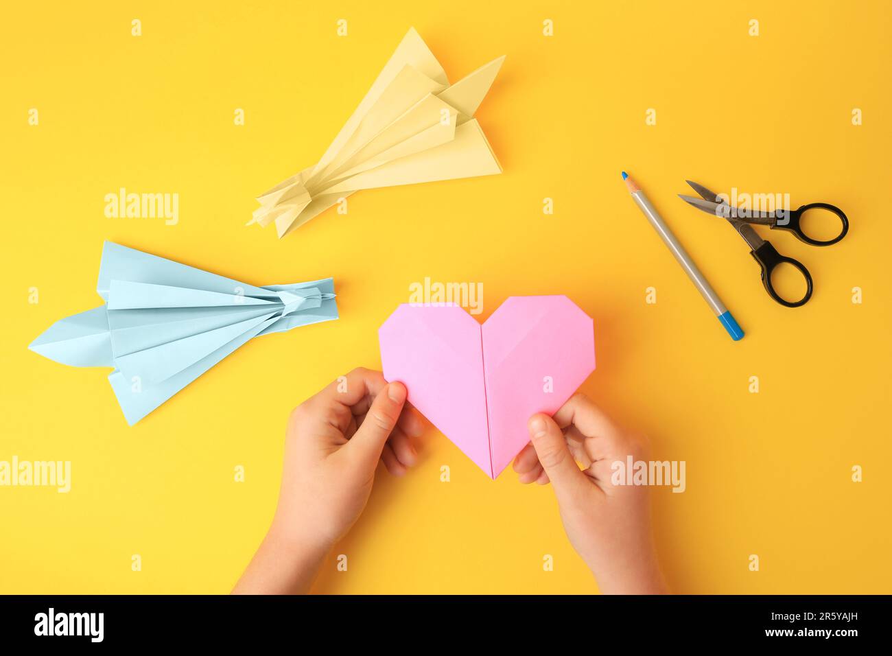 Origami art. Child holding paper figure on yellow background, closeup ...