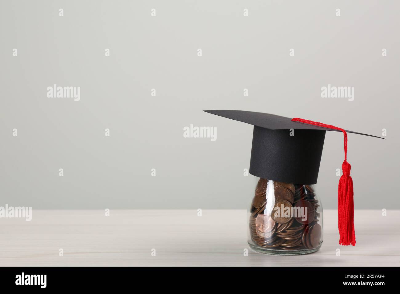 Scholarship concept. Graduation cap and coins on white wooden table ...
