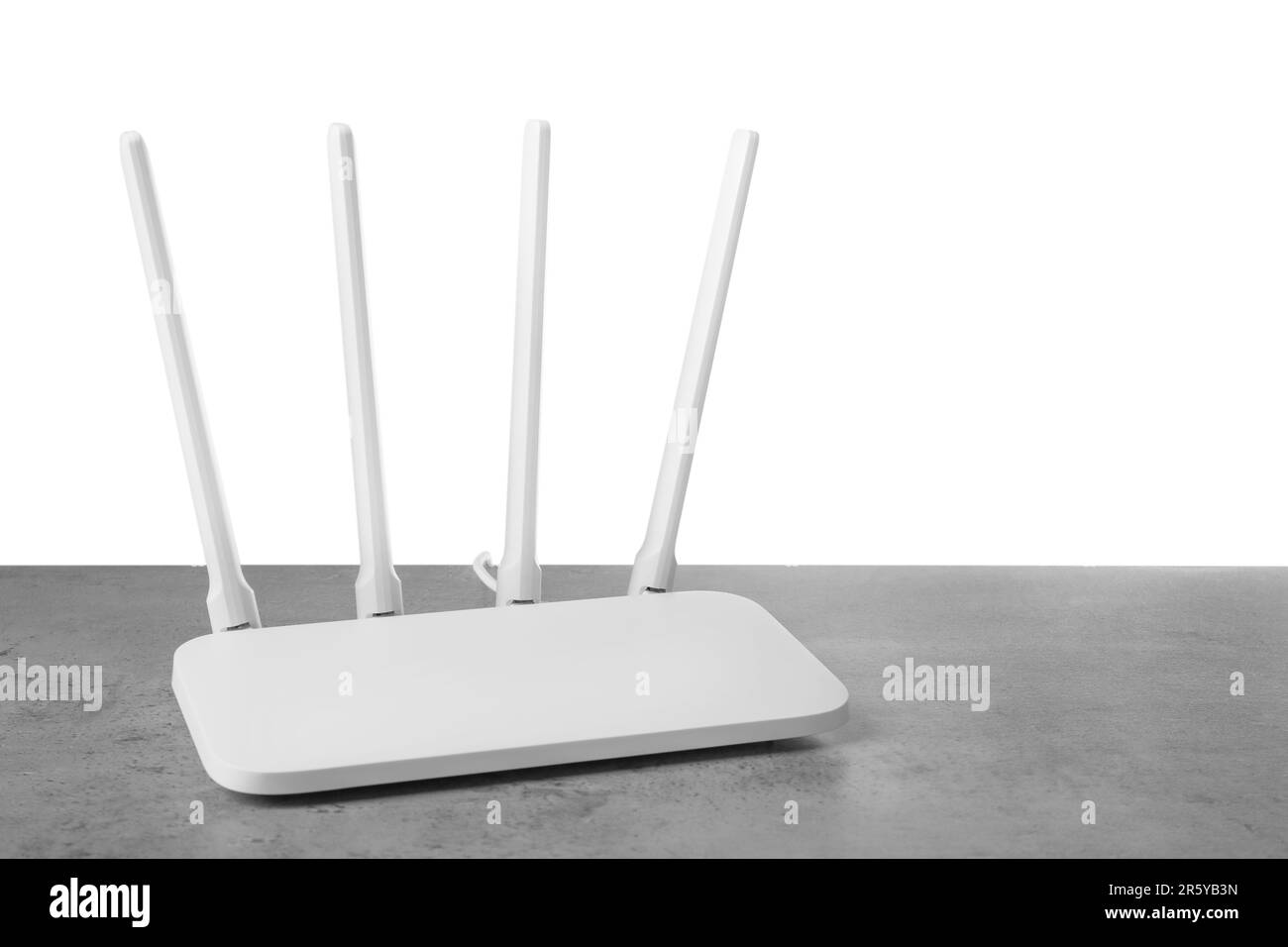 New modern Wi-Fi router on grey table against white background. Space ...