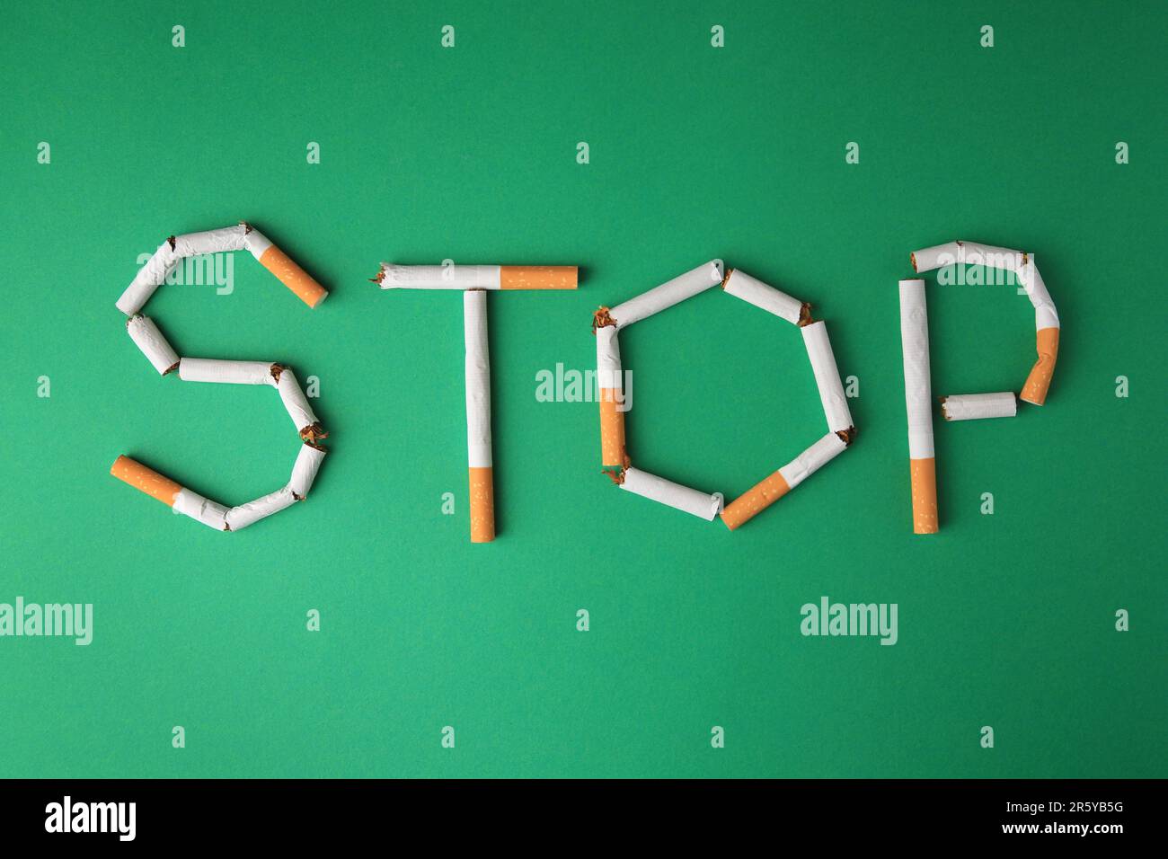 Word Stop made of broken cigarettes on green background, flat lay. Stop ...