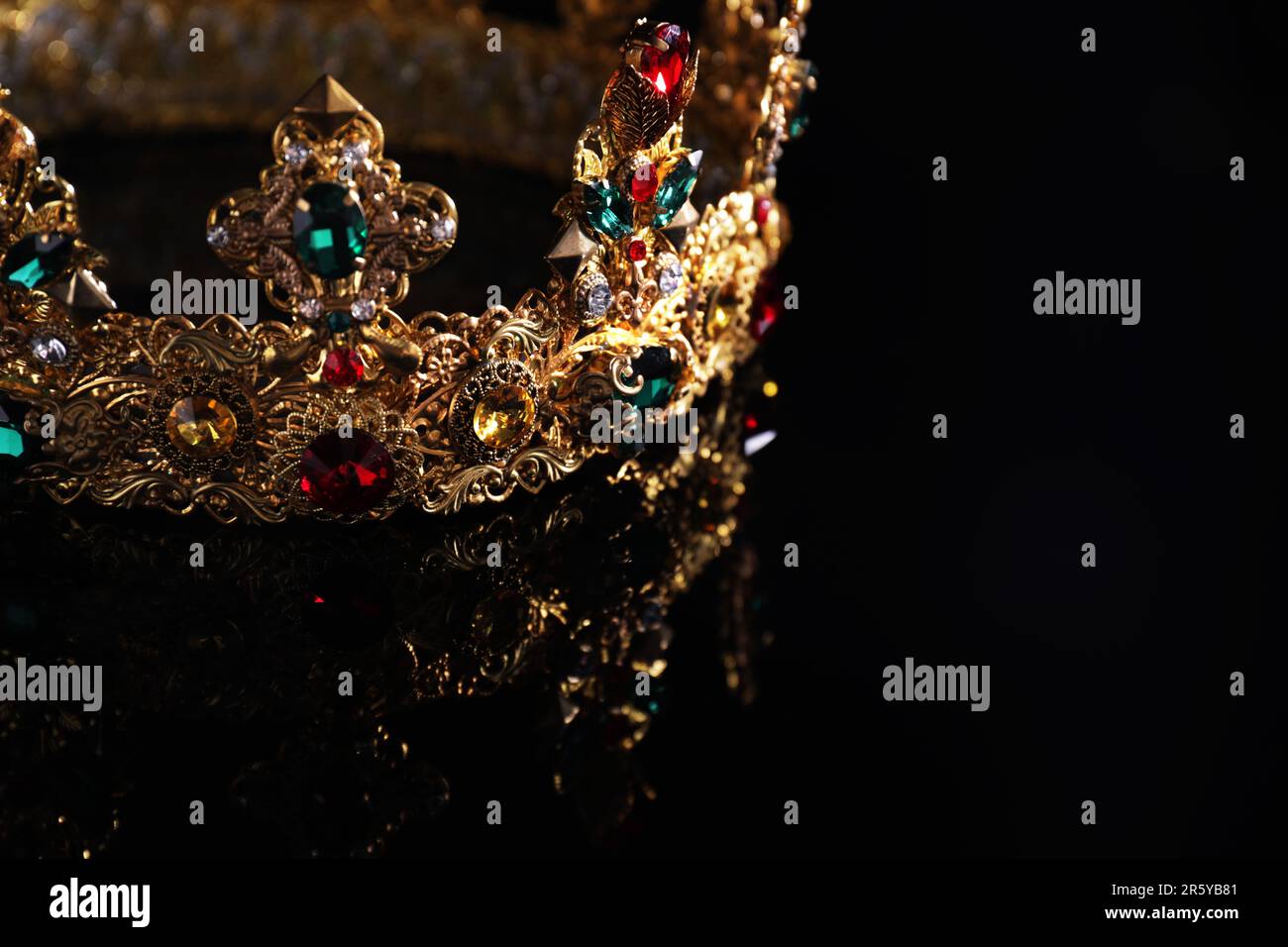 Beautiful golden crown with gems on dark mirror surface, closeup. Space ...