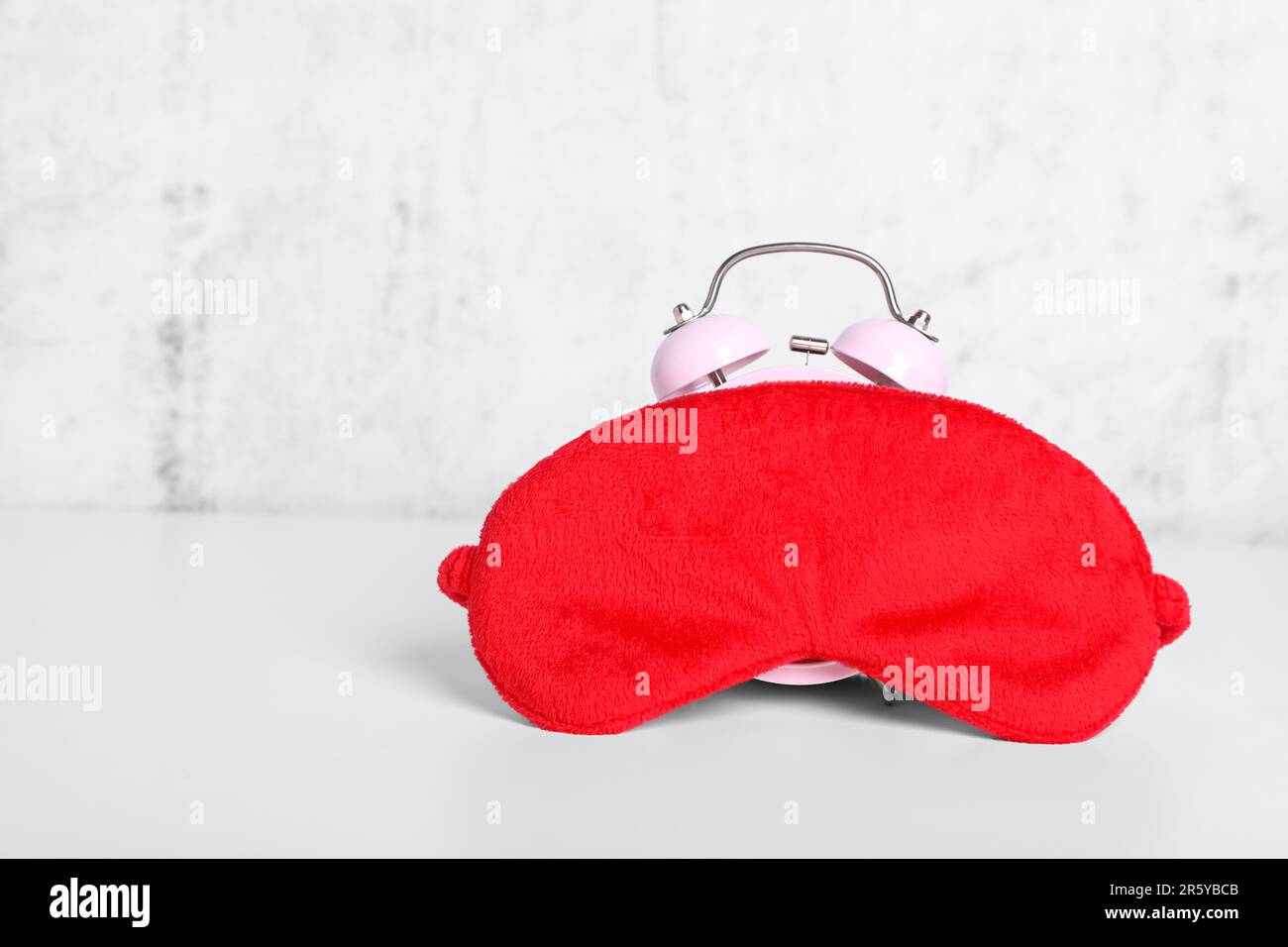Red sleep mask and alarm clock on white table. Space for text Stock ...