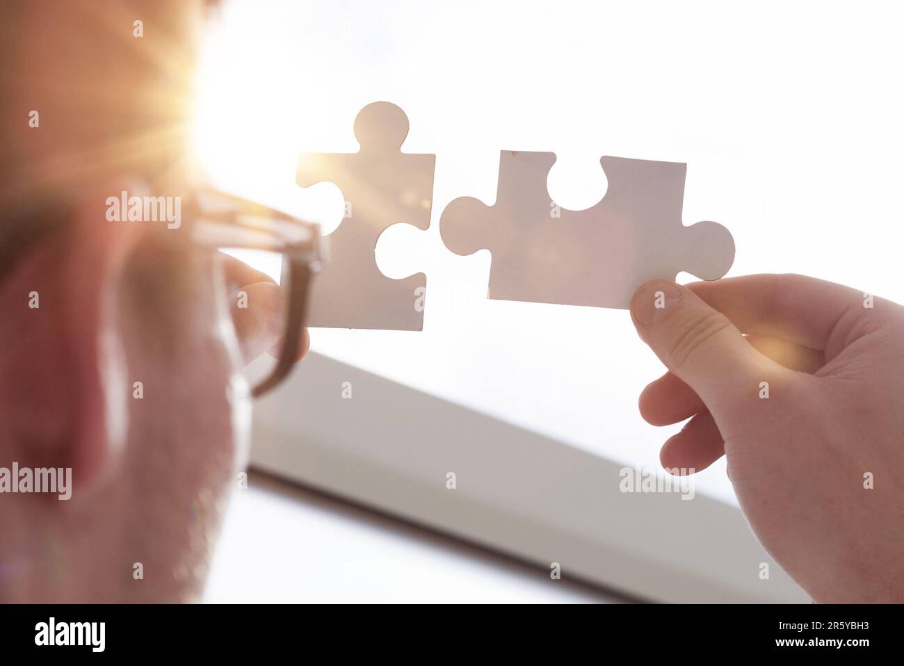 Businessman hands connecting puzzle pieces representing the merging of ...
