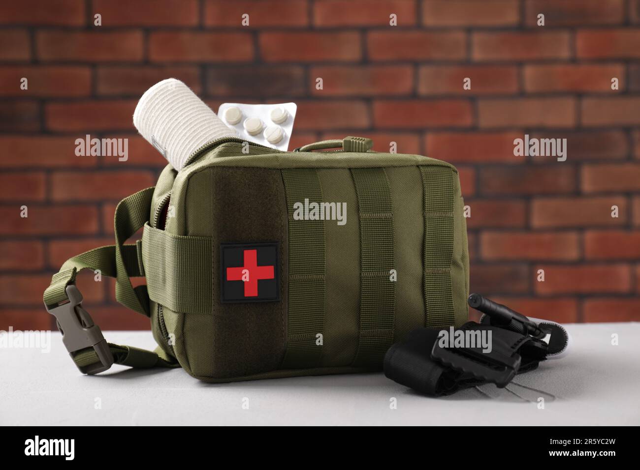 Military first aid kit, tourniquet and pills on white textured table ...