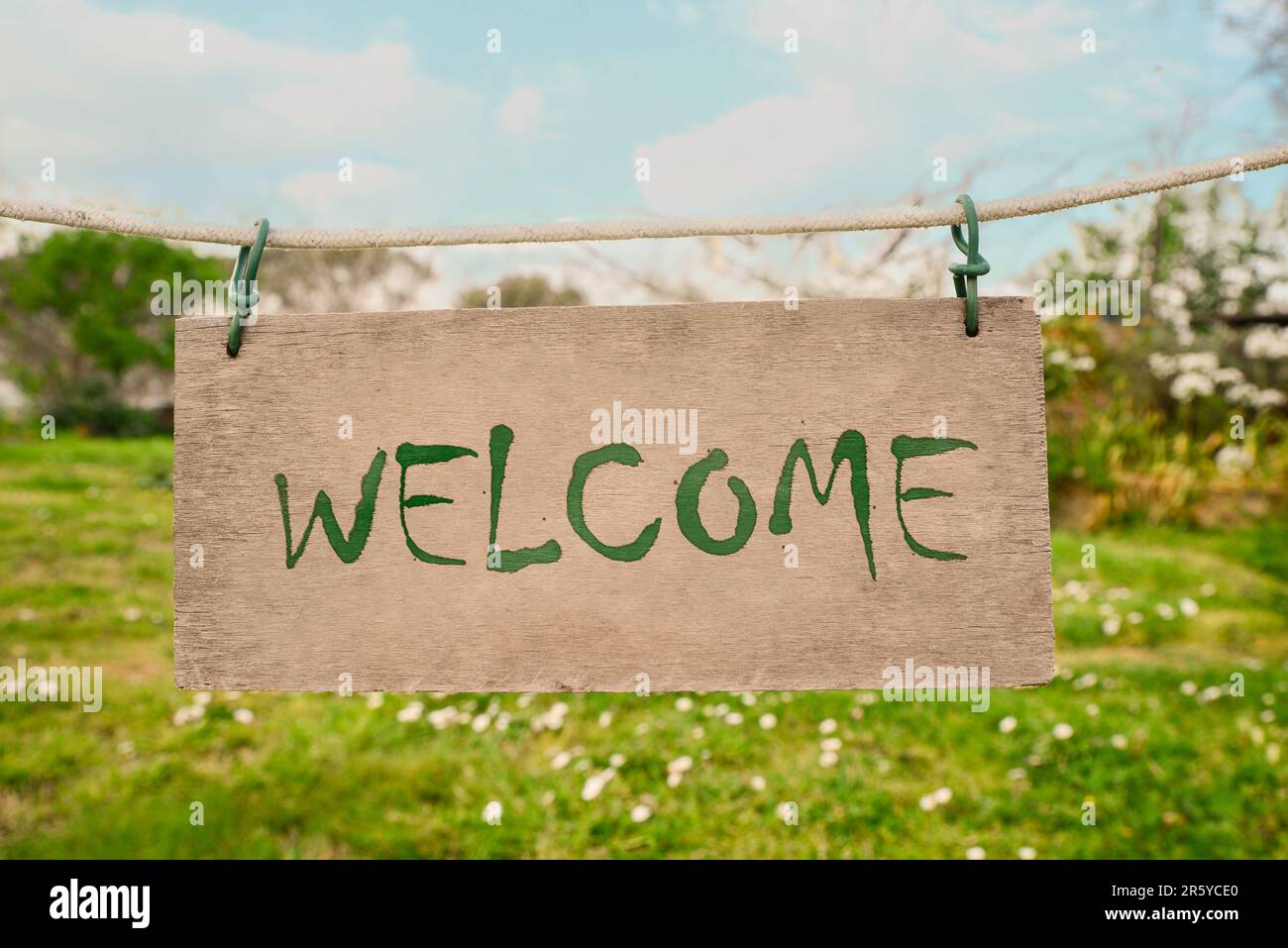 Welcome card. Wooden board with word hanging on rope in countryside ...
