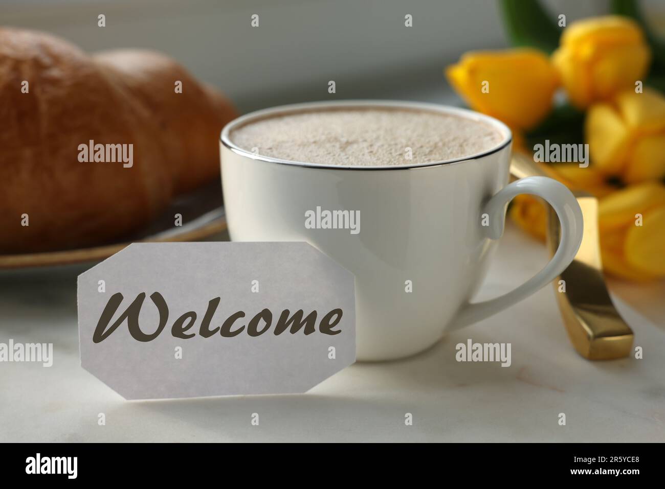 Welcome card, cup of aromatic coffee and croissant on tray and ...