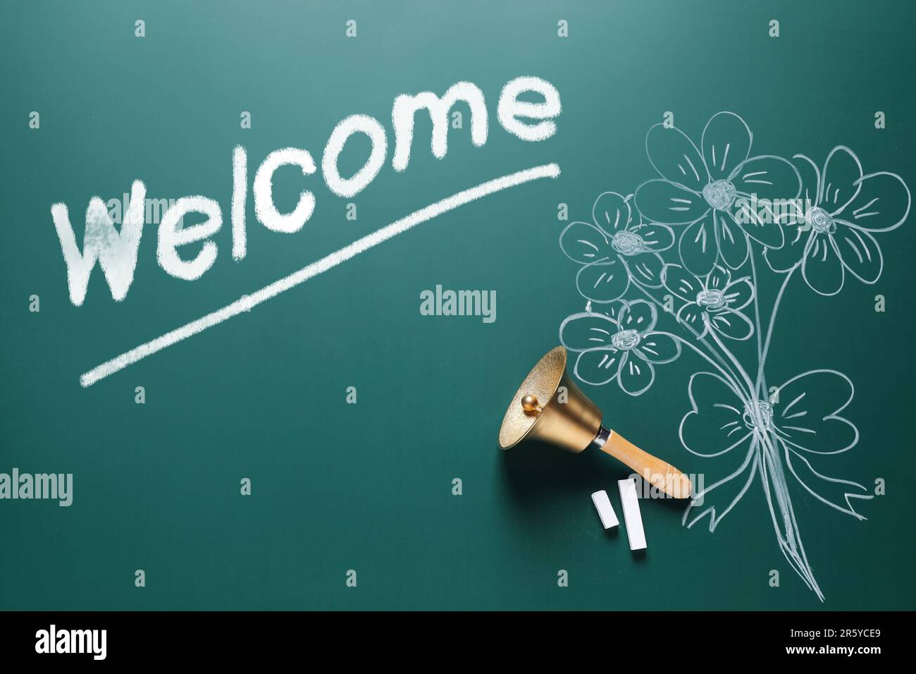 Welcome card. Golden bell, chalk, word and drawn flowers on green board ...