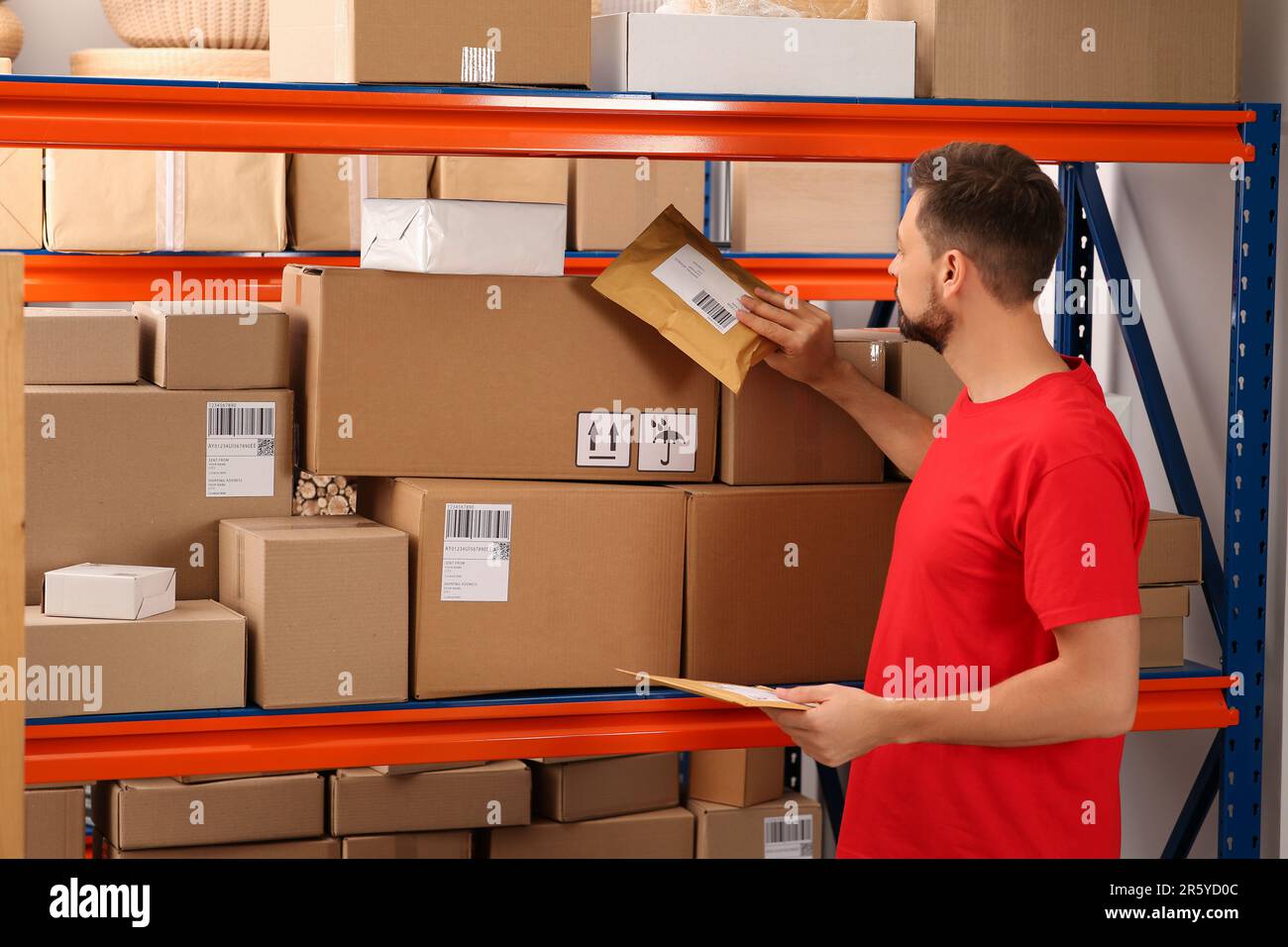 Post office worker holding adhesive paper bag near rack with parcels ...