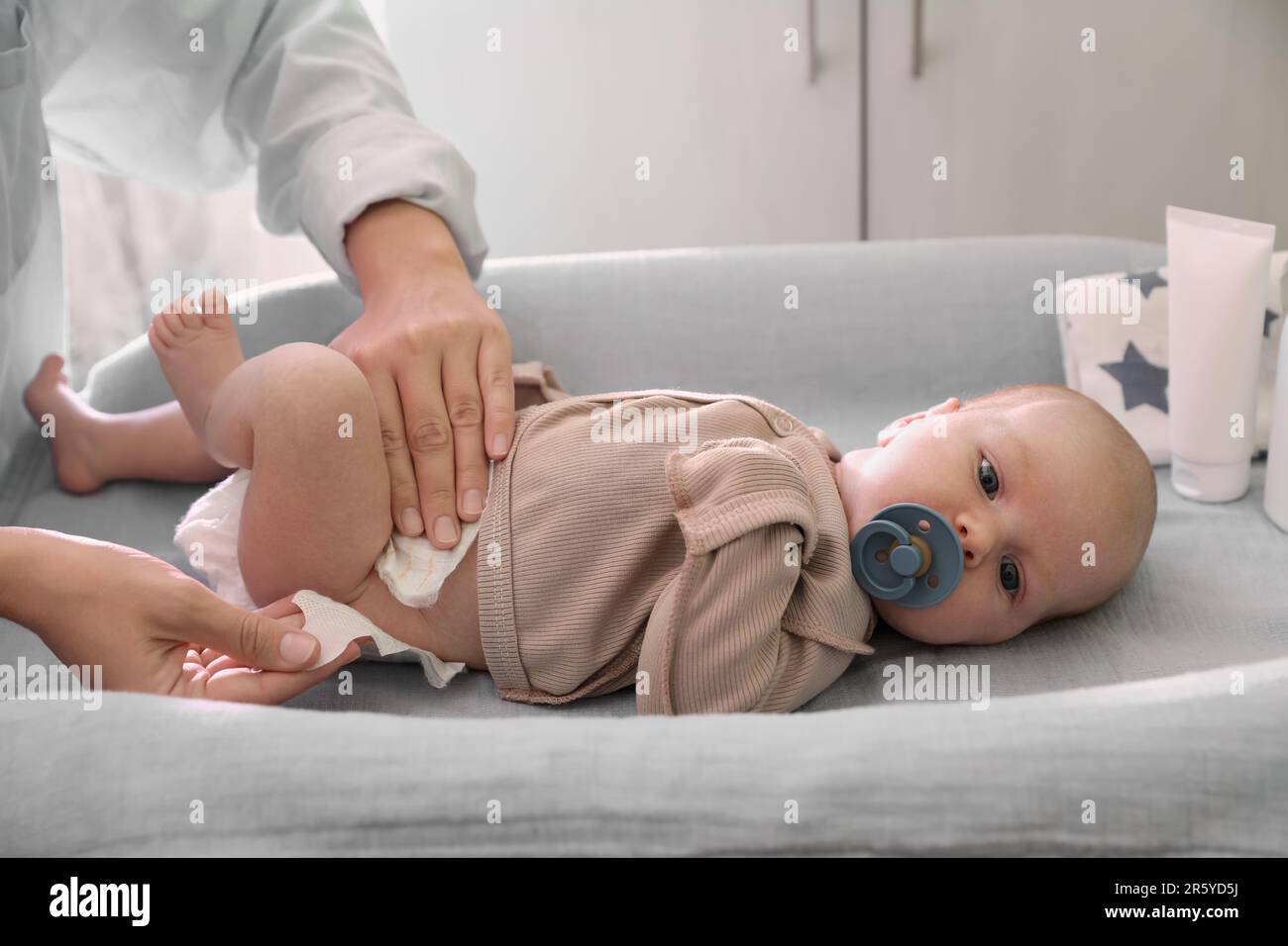 Mother changing baby's diaper on table in room, closeup Stock Photo - Alamy