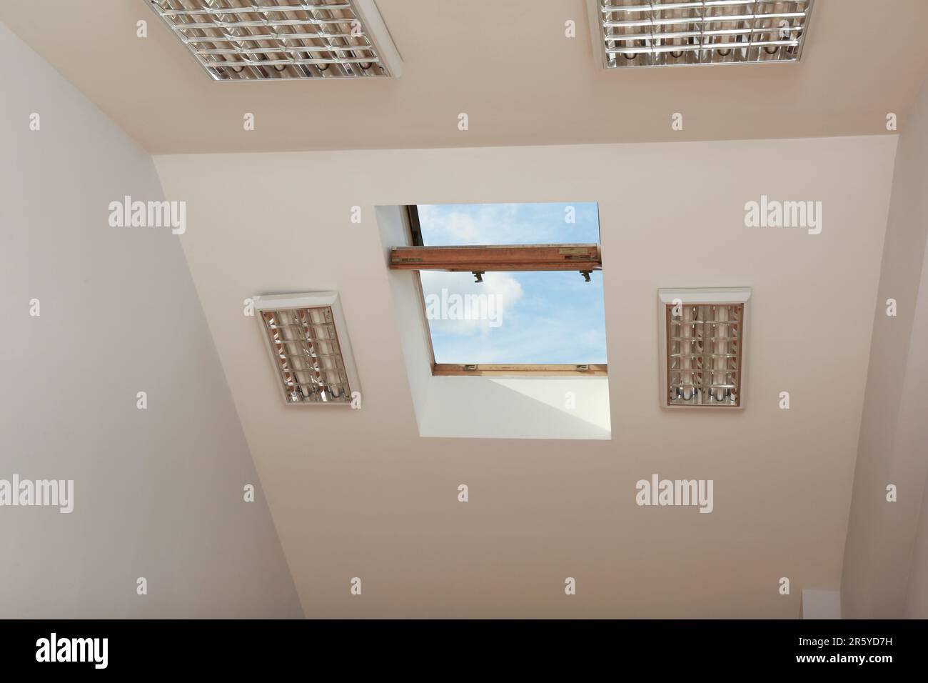 Open skylight roof window on slanted ceiling in attic room, low angle ...
