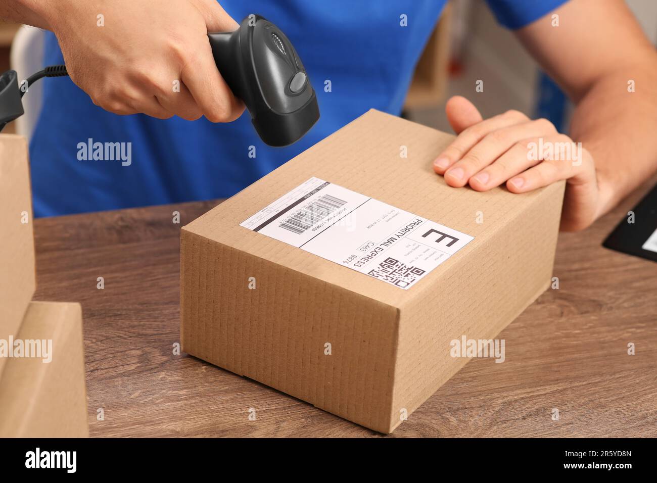 Post office worker with scanner reading parcel barcode at counter ...