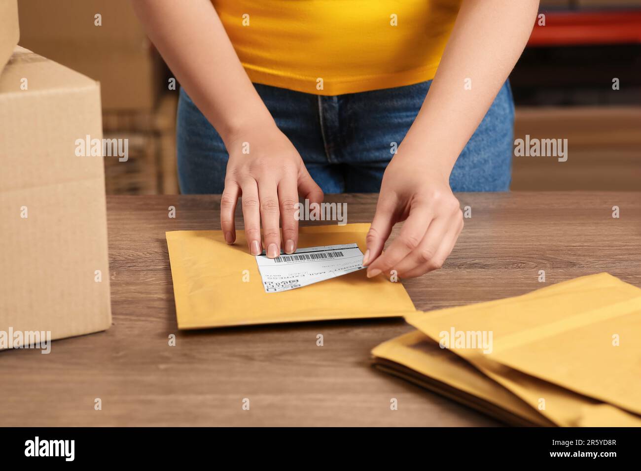 Post office worker sticking barcode on parcel at counter indoors ...